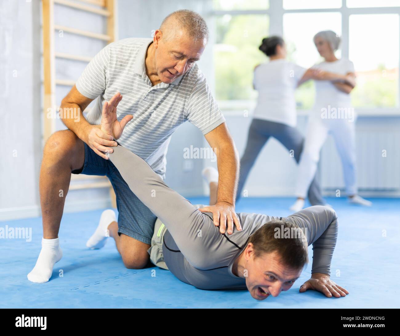 Old man twisting her opponent's arm during self-defense classes Stock ...