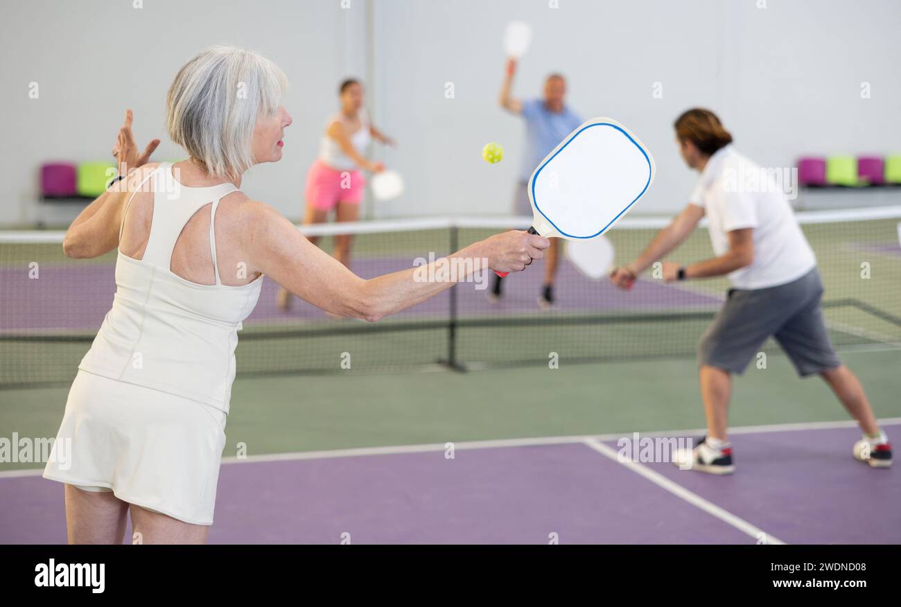 Rear view of sporty senior woman playing pickleball indoors Stock Photo ...