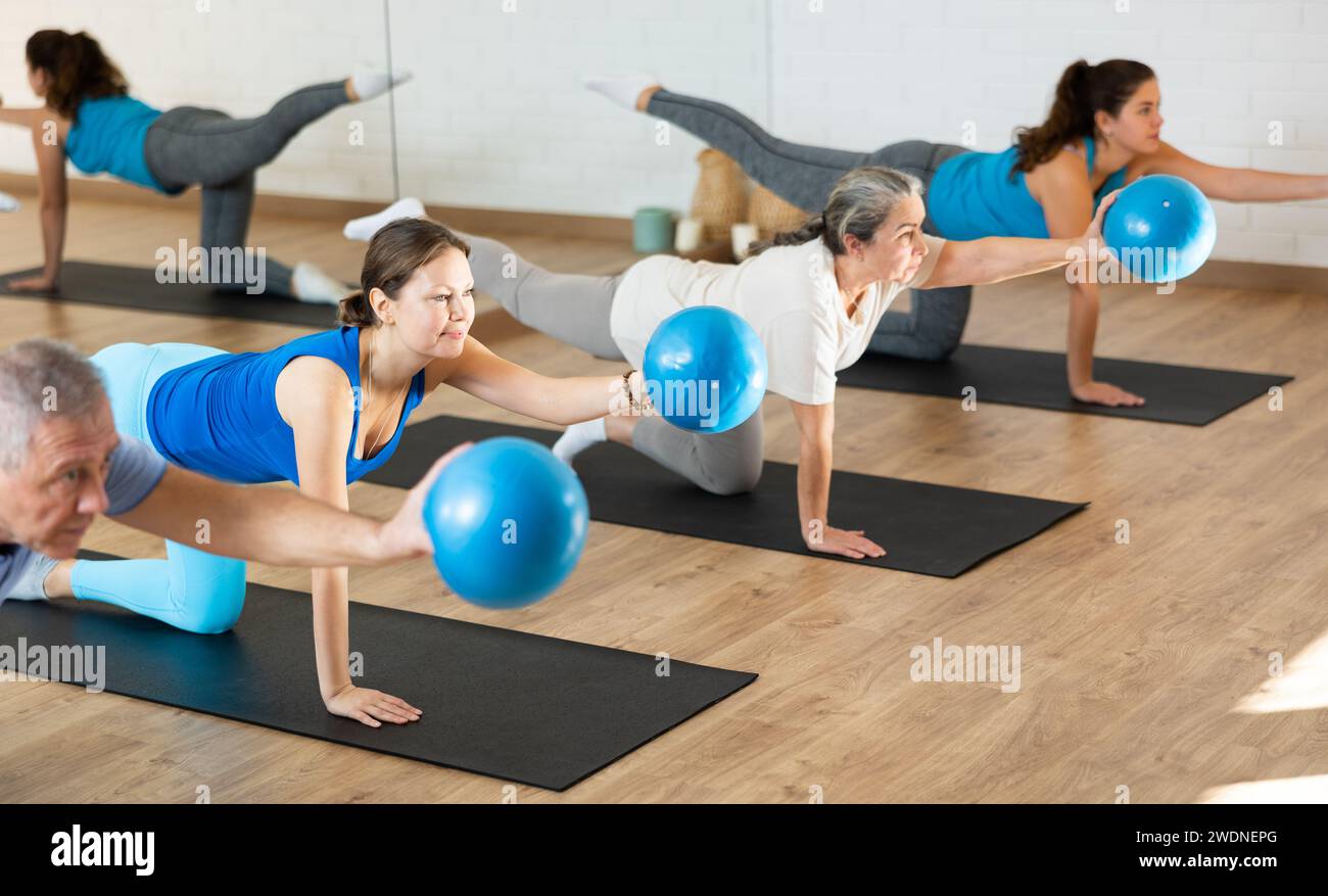 People of different ages stretching leg and arm, holding mini ball in ...