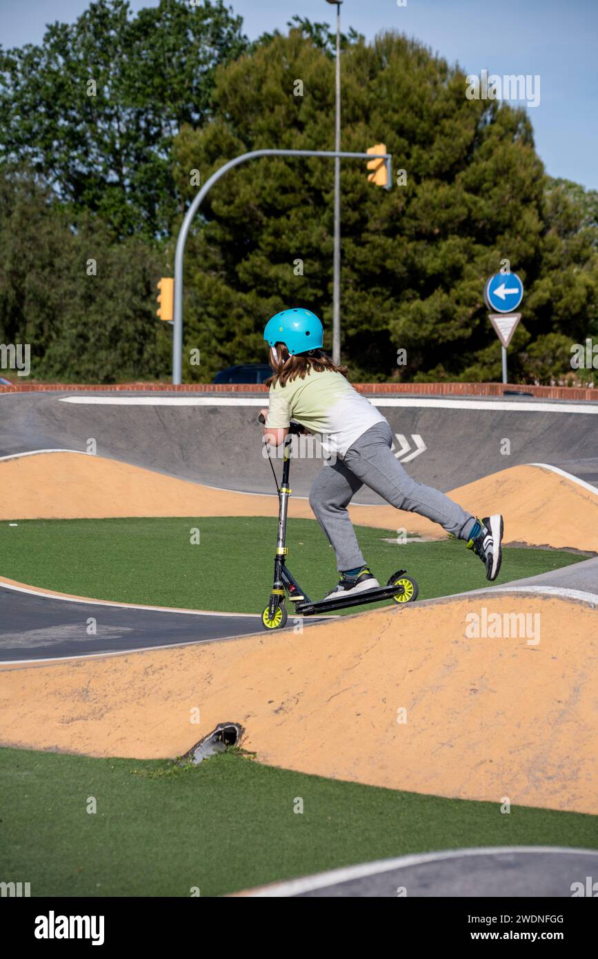 Sunny pumptrack thrill: Vertical shot of a kid with a blue helmet ...