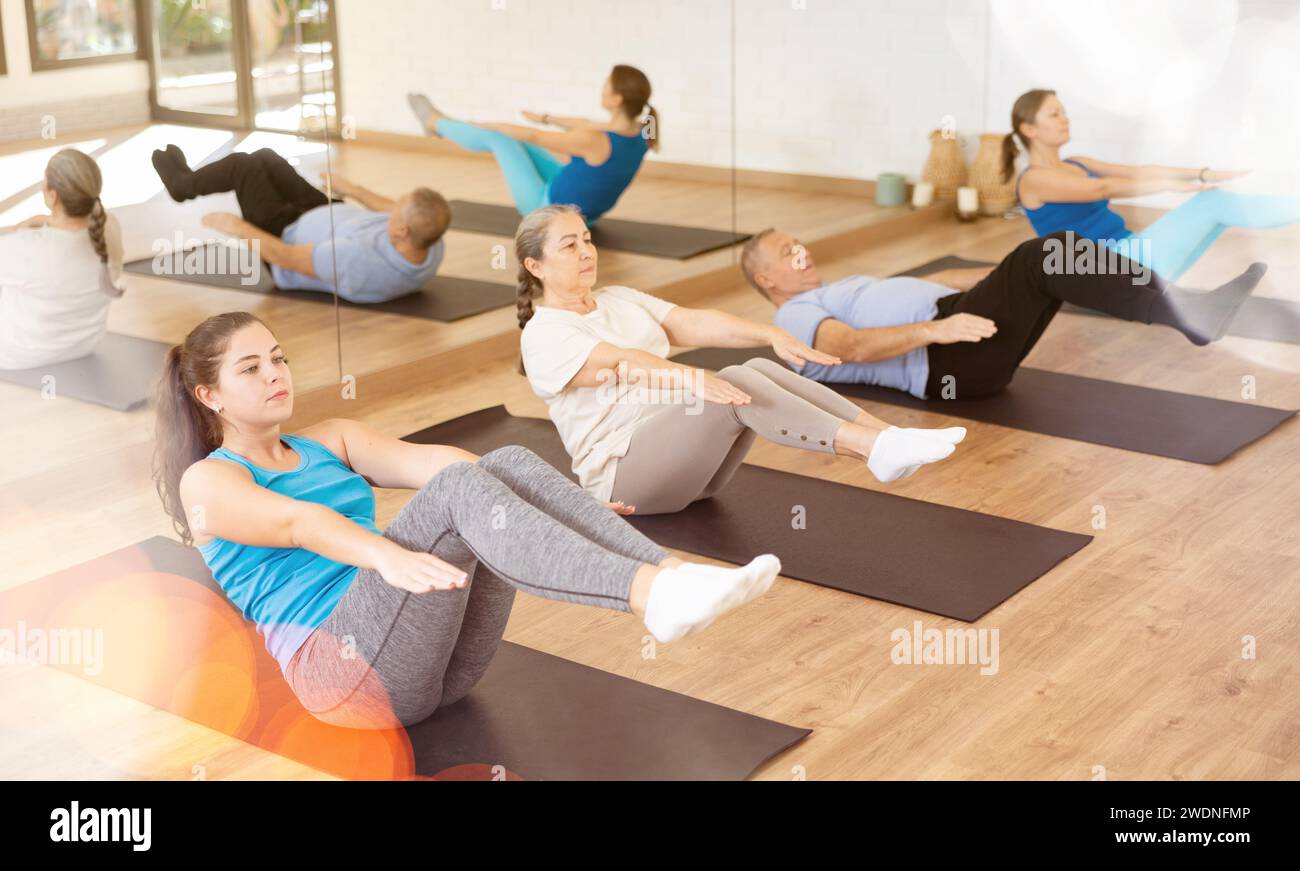 Young girl performing balancing V-sit during group workout Stock Photo ...