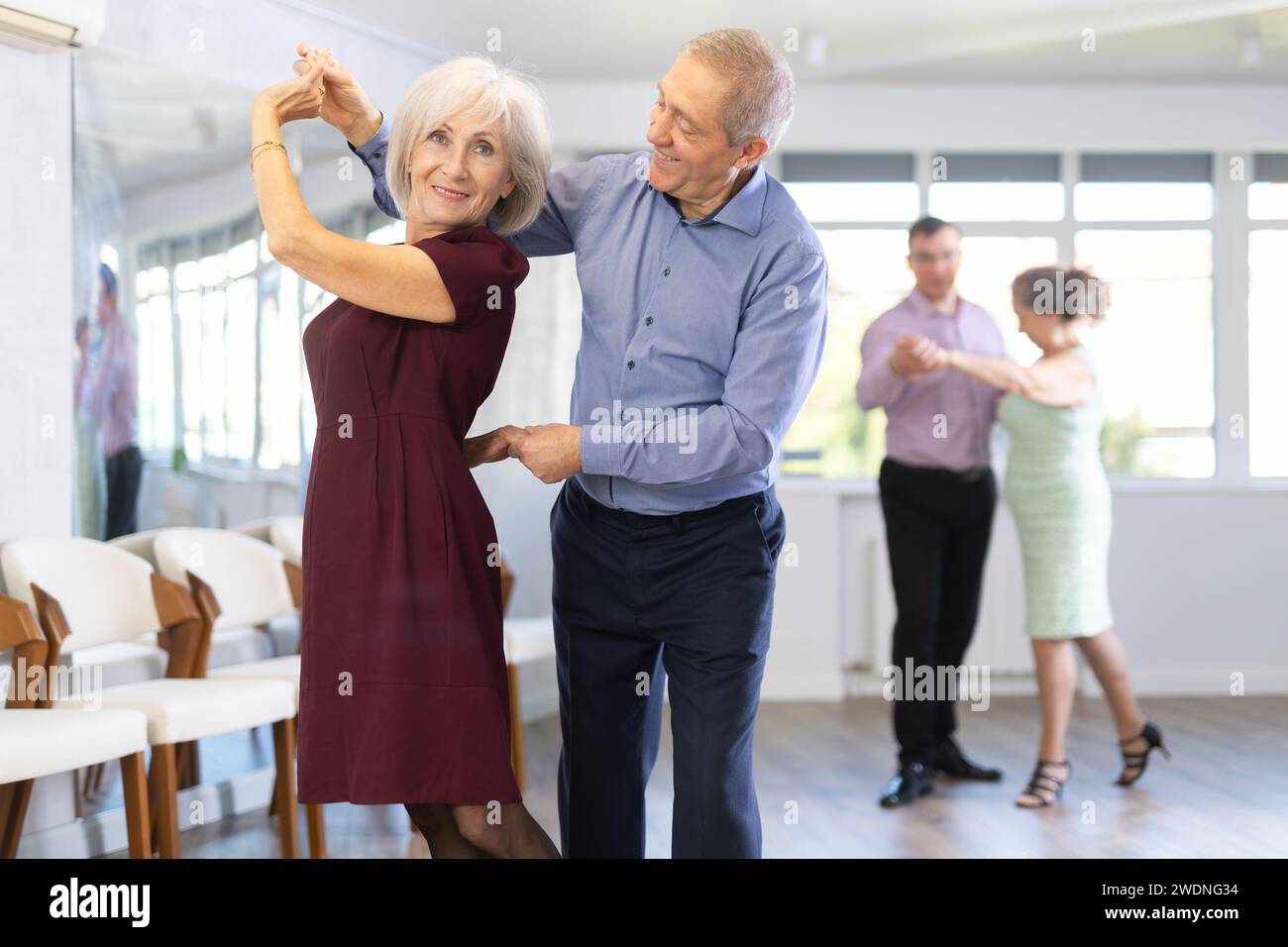 Happy mature woman enjoying impassioned merengue with male partner in dance class. Social ...