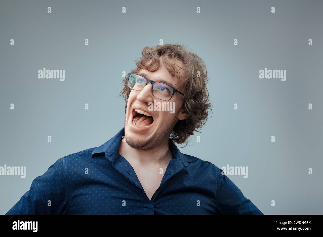 Curly-haired man with glasses expresses overwhelming joy, mouth wide ...