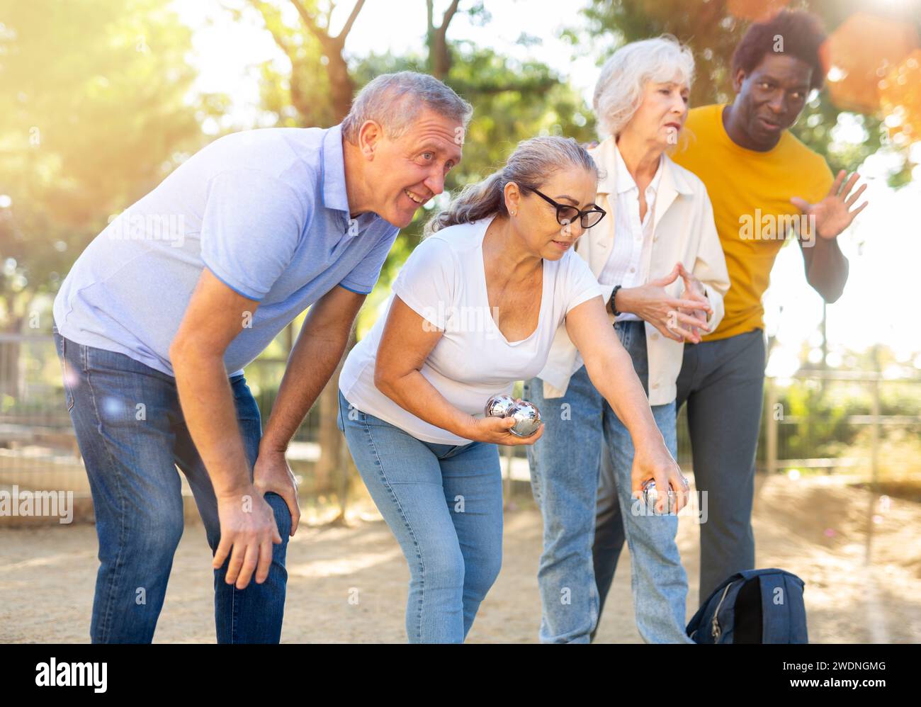 A group of multiracial mature adult people playing patanque game ...