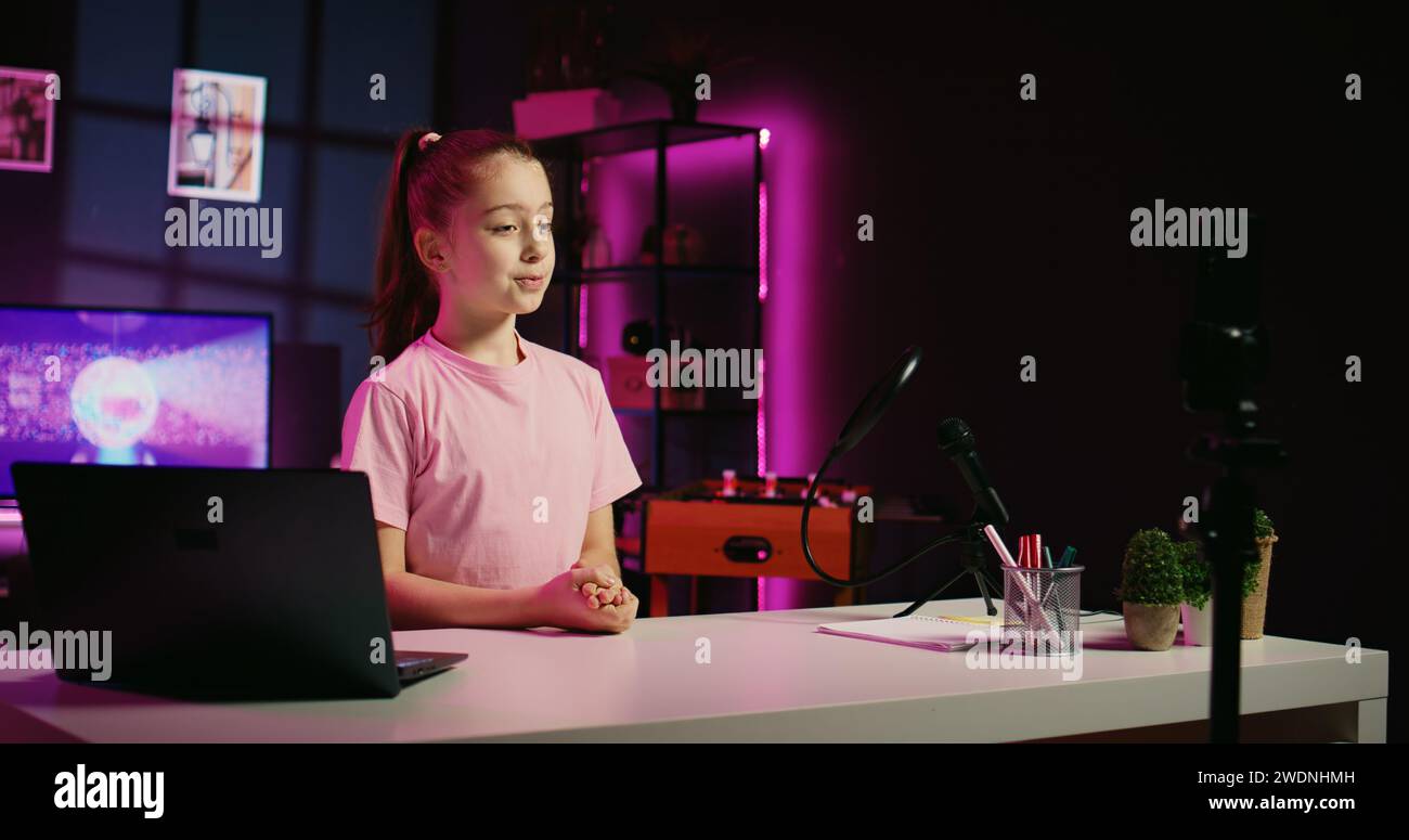 Joyous kid talking about school with children audience, filming content ...