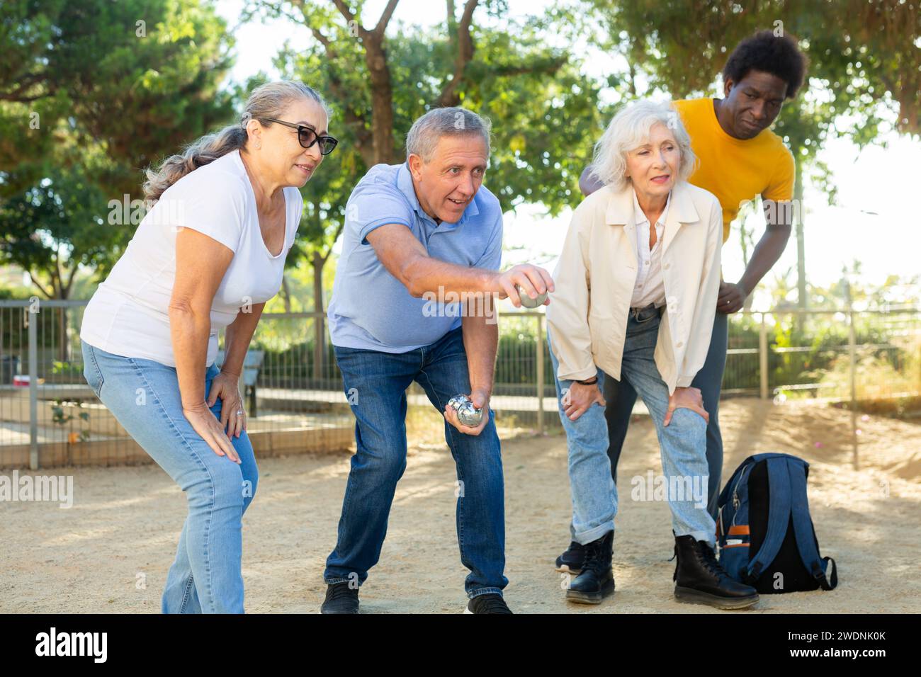 A group of multiracial mature adult people playing patanque game ...