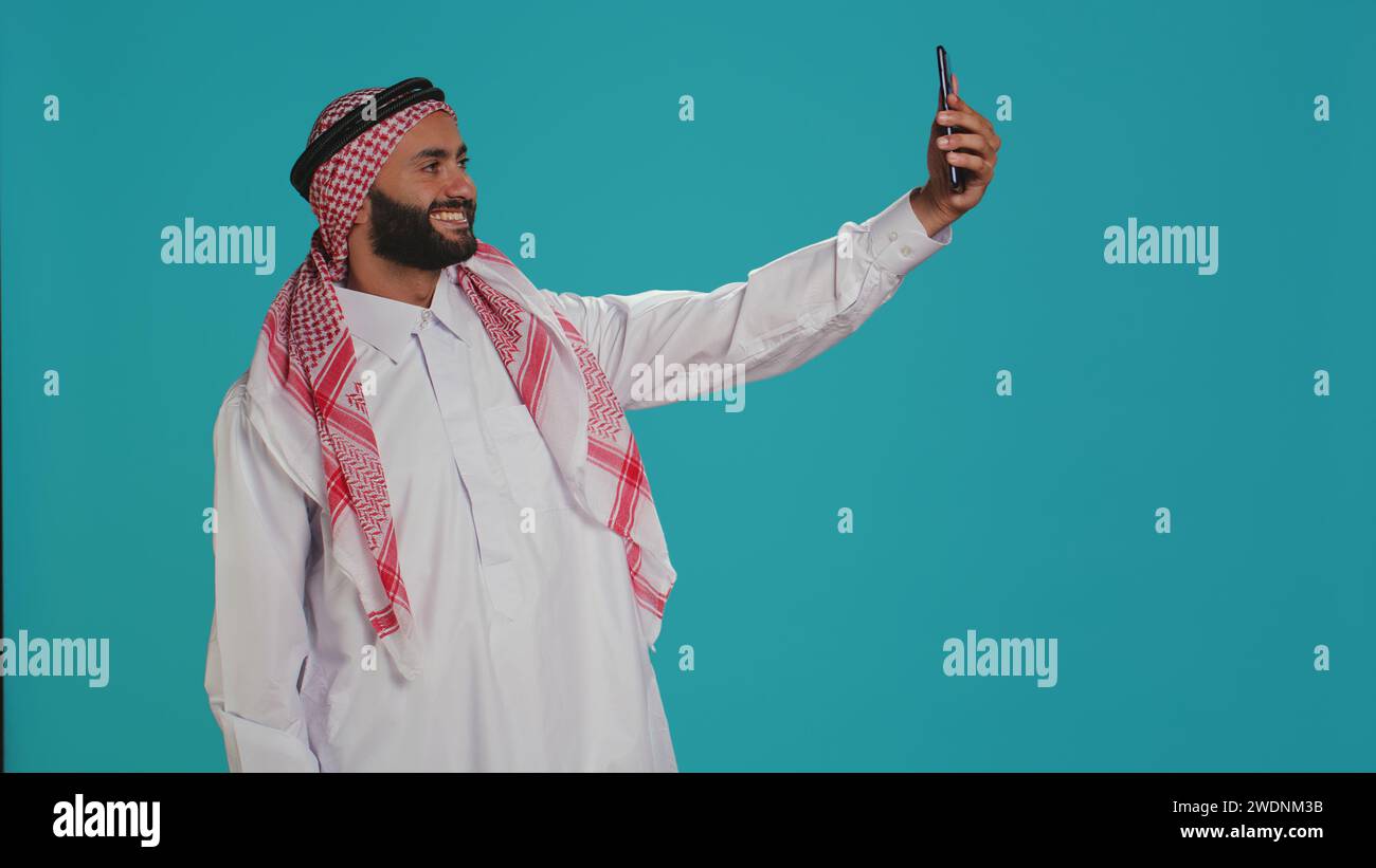 Arab man takes pictures with smartphone, laughing in studio using ...