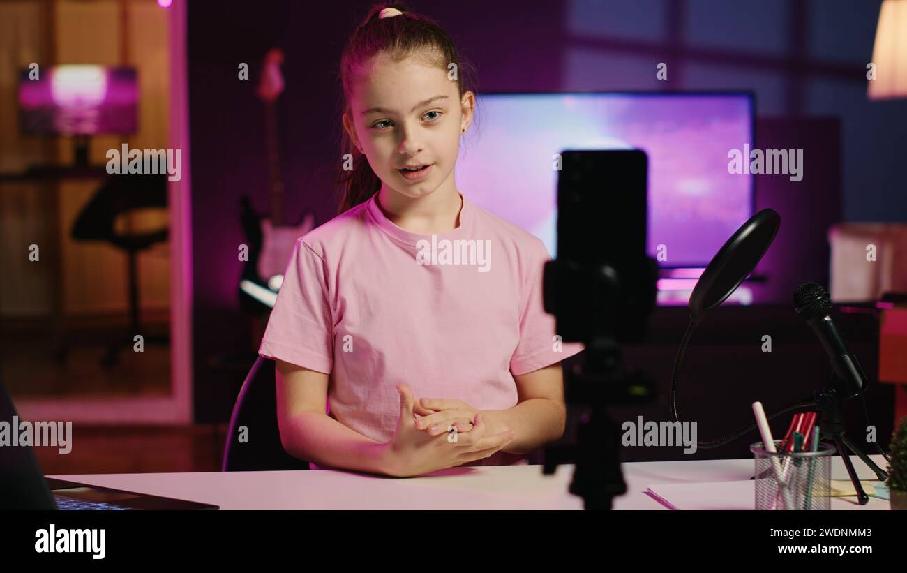 Kid filming with smartphone on tripod stabilizer in pink neon lit ...