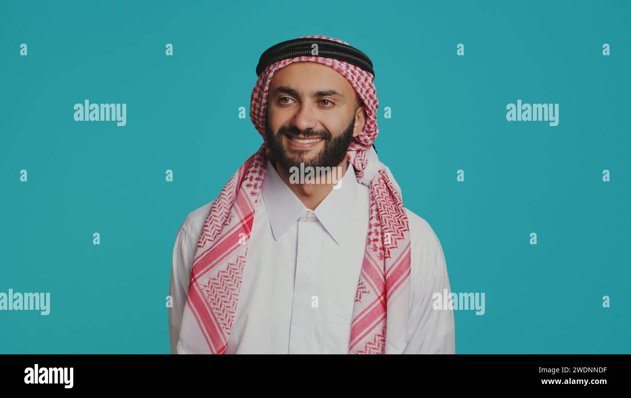 Muslim adult in traditional arabic wear, smiling and standing with ...