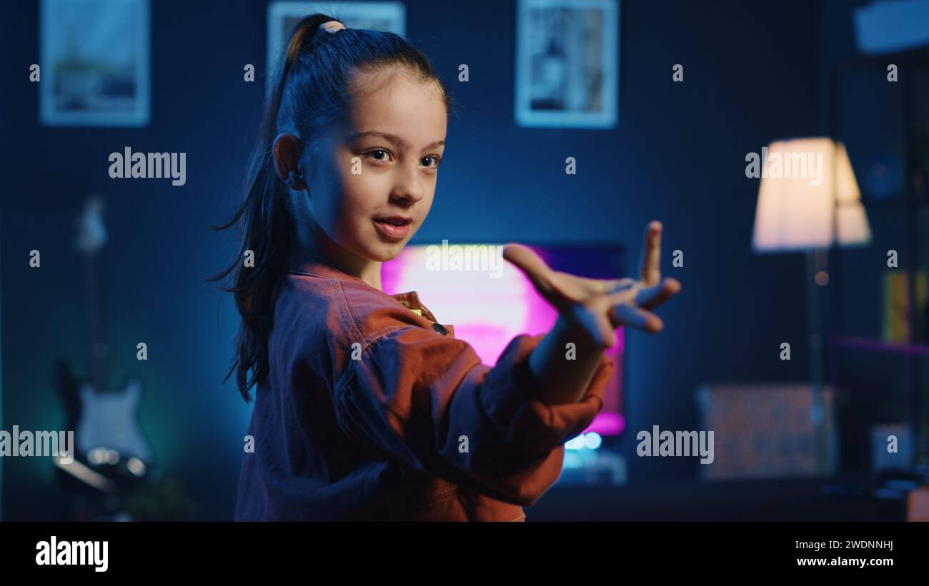 Close up shot of smiling kid dancing in dimly lit home studio interior ...