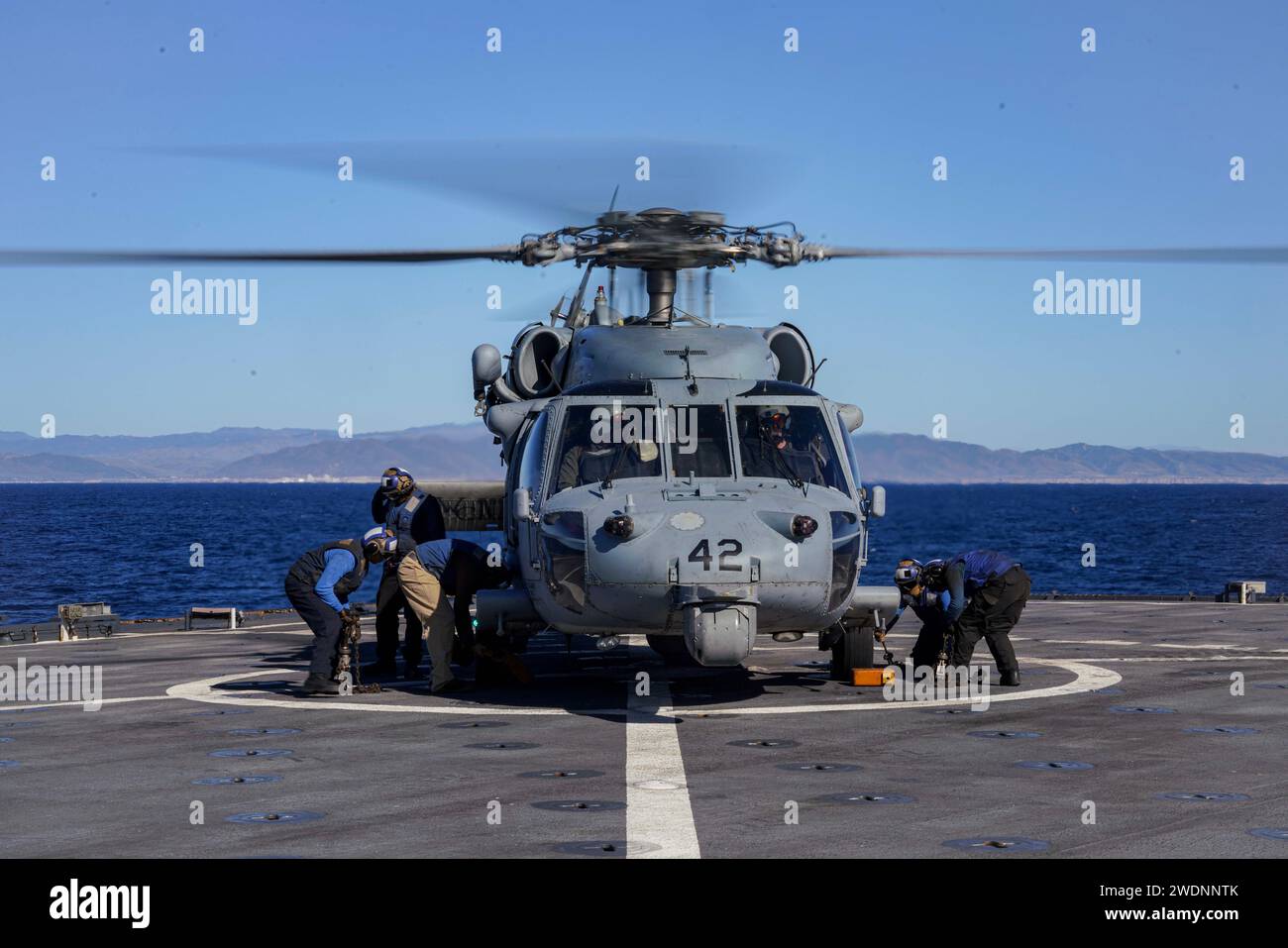 Sailors use chocks and chains to secure an SH-60S Seahawk, attached to ...