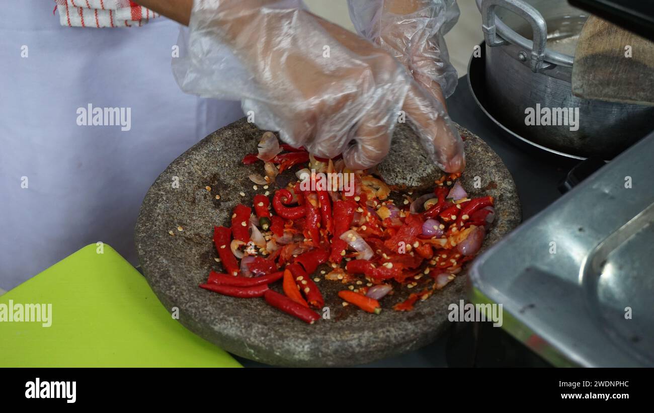 The chef is pounding chili sauce. Sambal is a famous food from ...