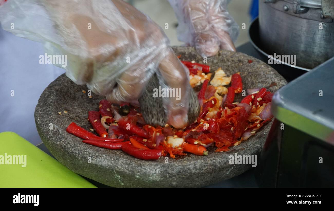 The chef is pounding chili sauce. Sambal is a famous food from ...