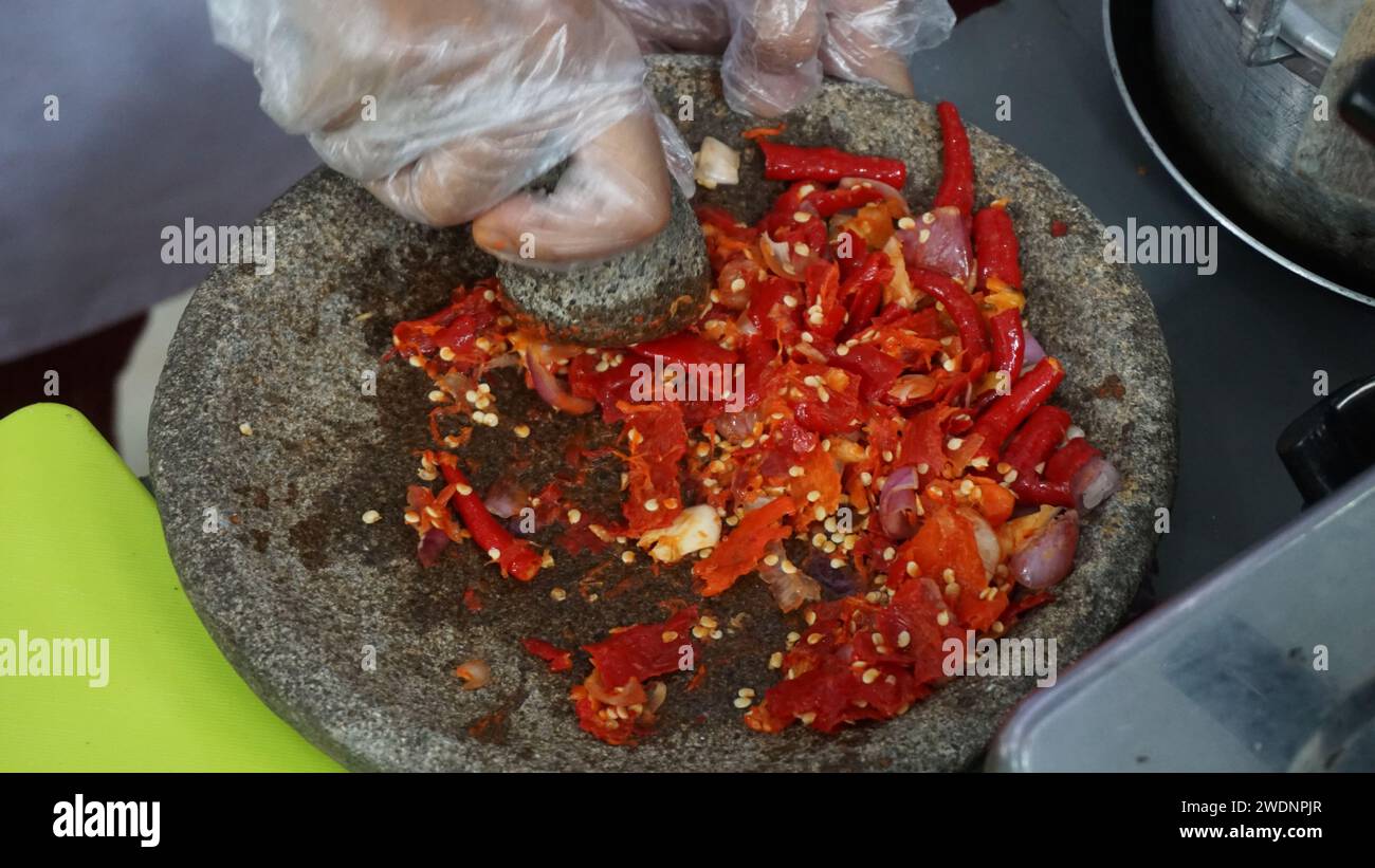 The chef is pounding chili sauce. Sambal is a famous food from ...