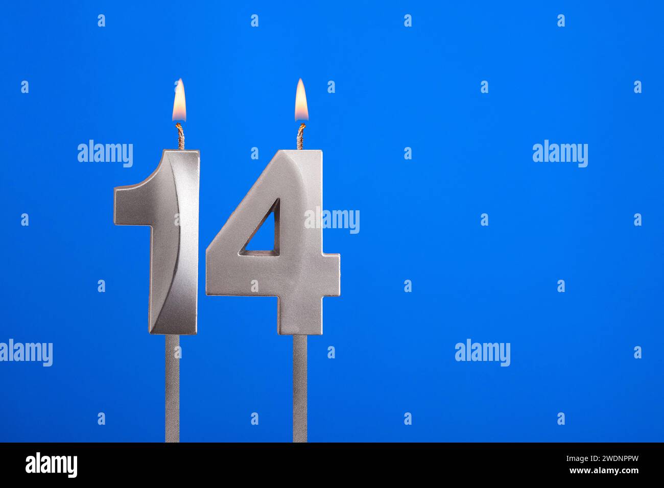 Birthday number 14 - Candle lit on blue background Stock Photo - Alamy