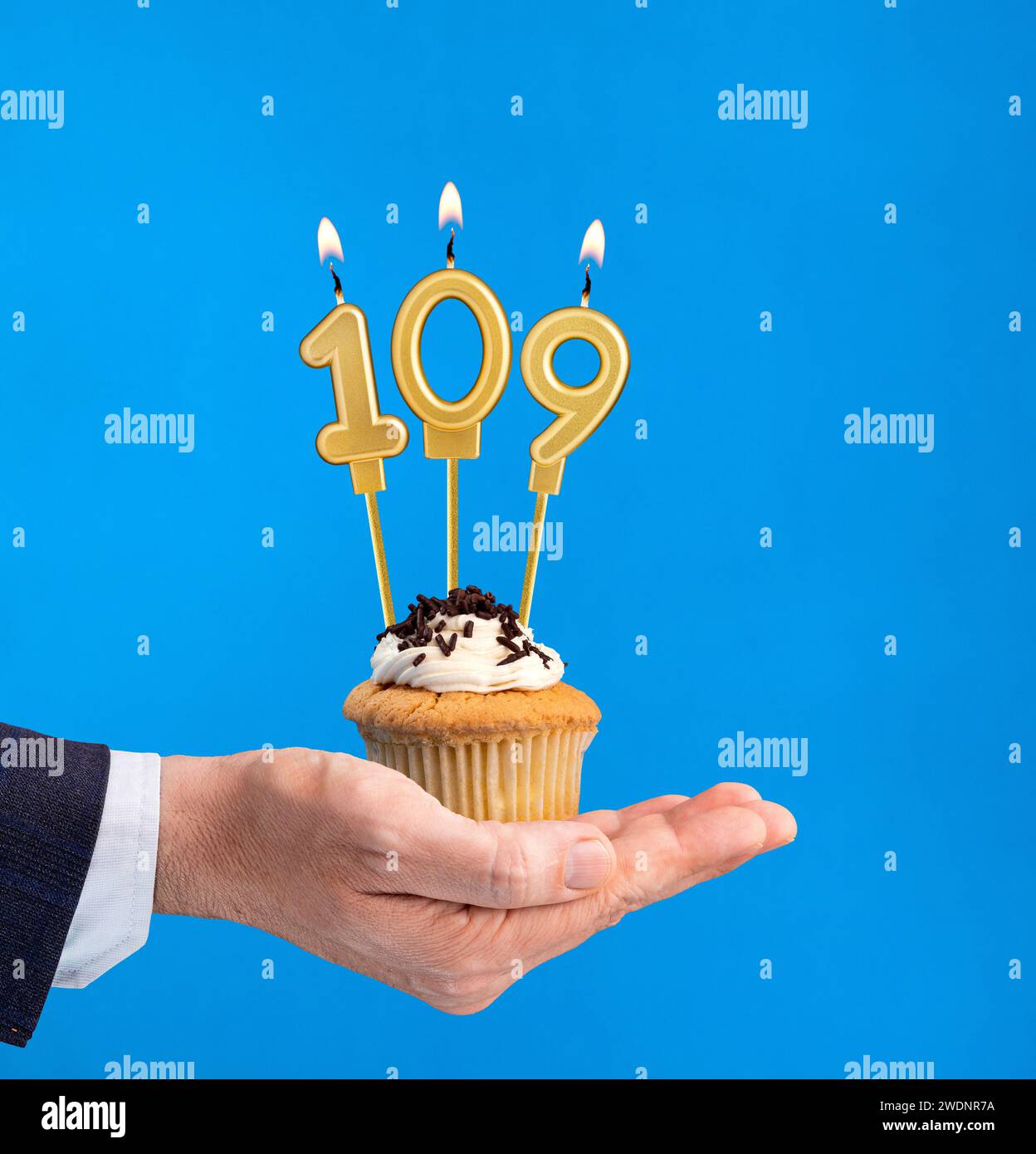 Hand holding a cupcake with the number 109 candle - Birthday on blue ...