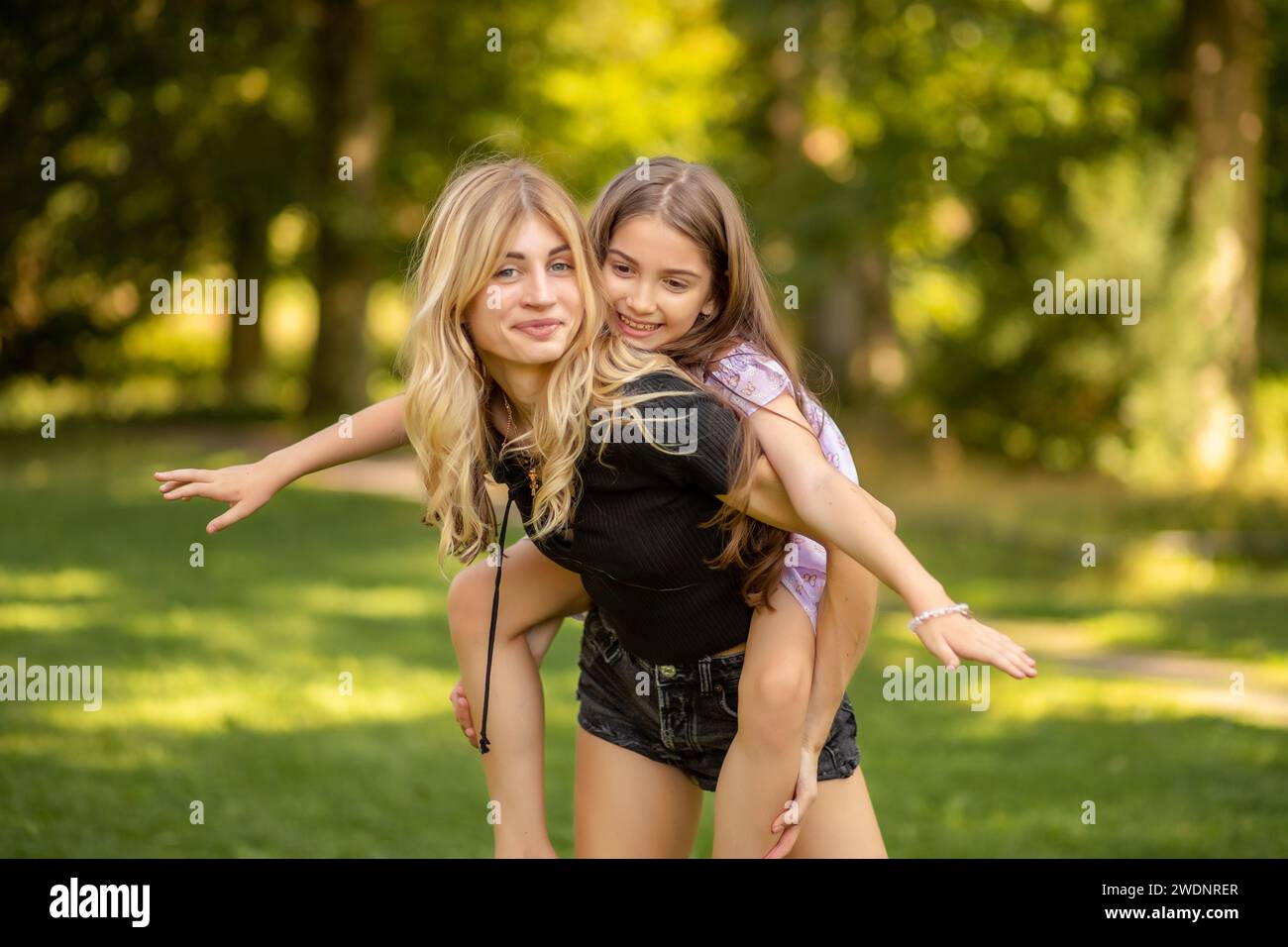 Mother carrying daughter on her back, both smiling Stock Photo - Alamy