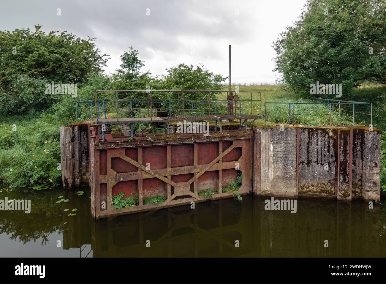 An ancient, very old metal rusted water sluice, by the river bank in ...
