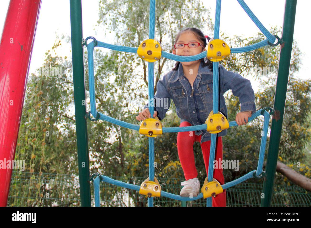 4-year-old Latin brunette girl plays in a playground, does physical ...