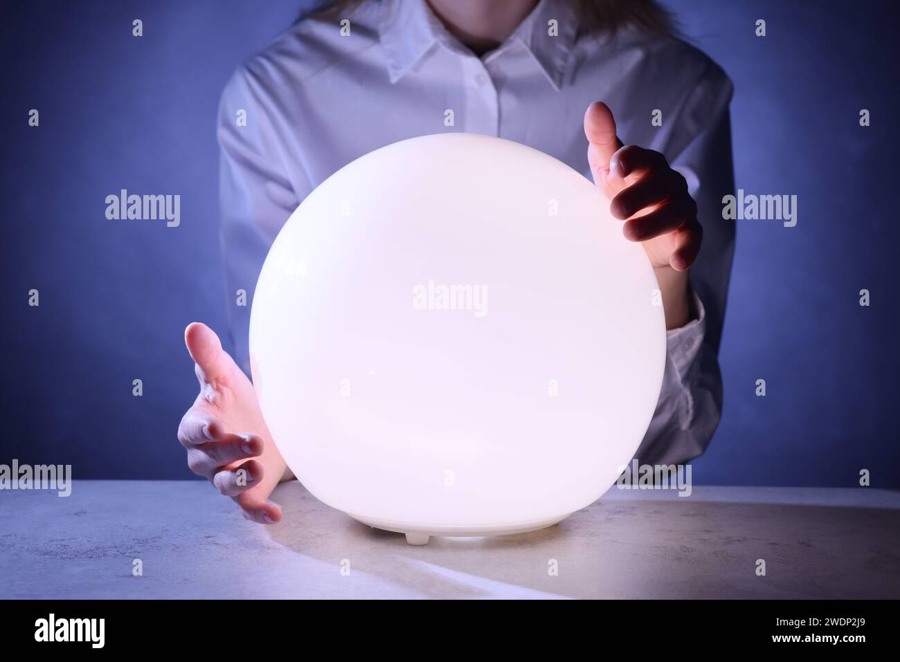 Businesswoman using glowing crystal ball to predict future at table ...