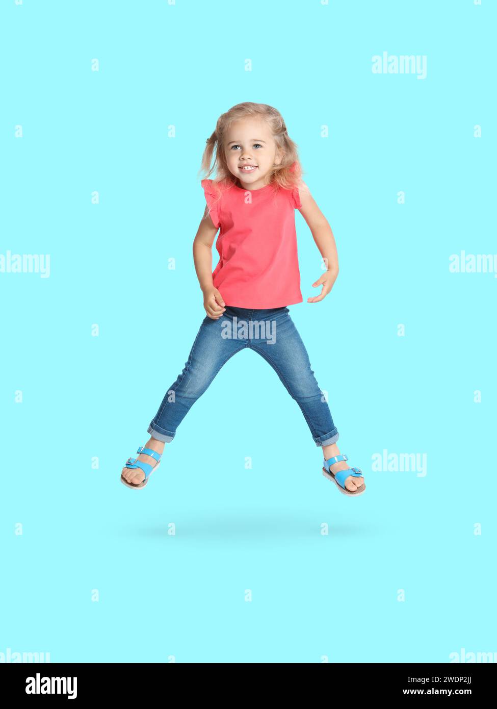 Happy cute girl jumping on light blue background Stock Photo - Alamy
