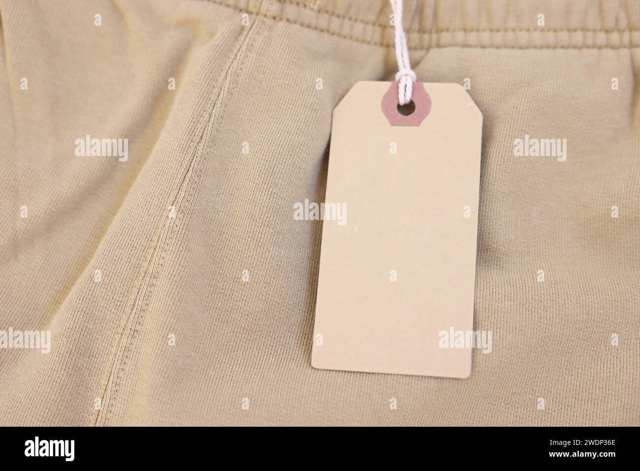 Cardboard tag on beige pants, closeup. Space for text Stock Photo - Alamy