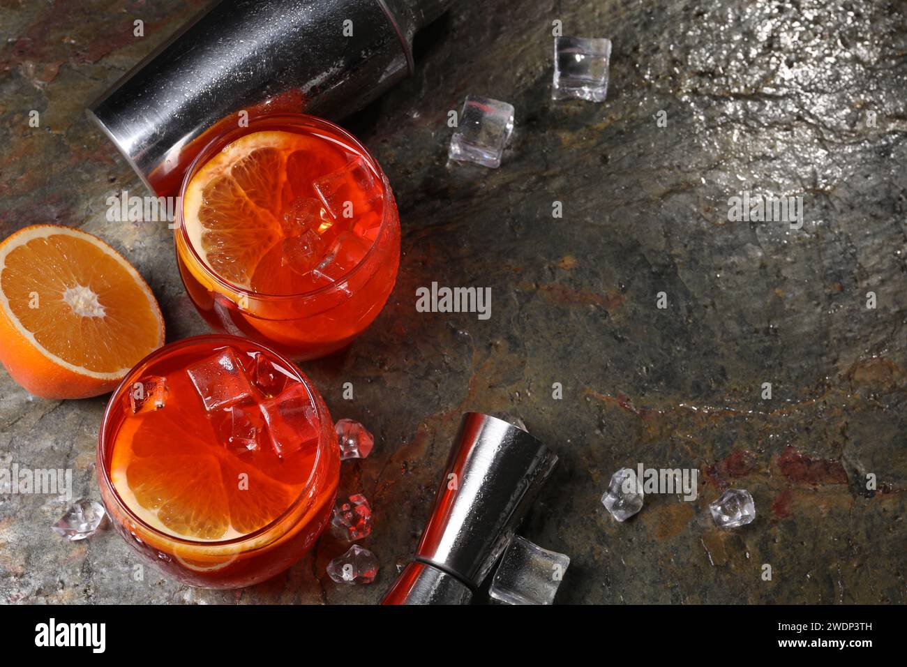 Aperol spritz cocktail, ice cubes and orange slices in glasses on grey ...