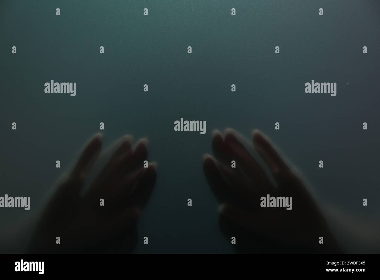 Silhouette of creepy ghost behind glass against color background ...