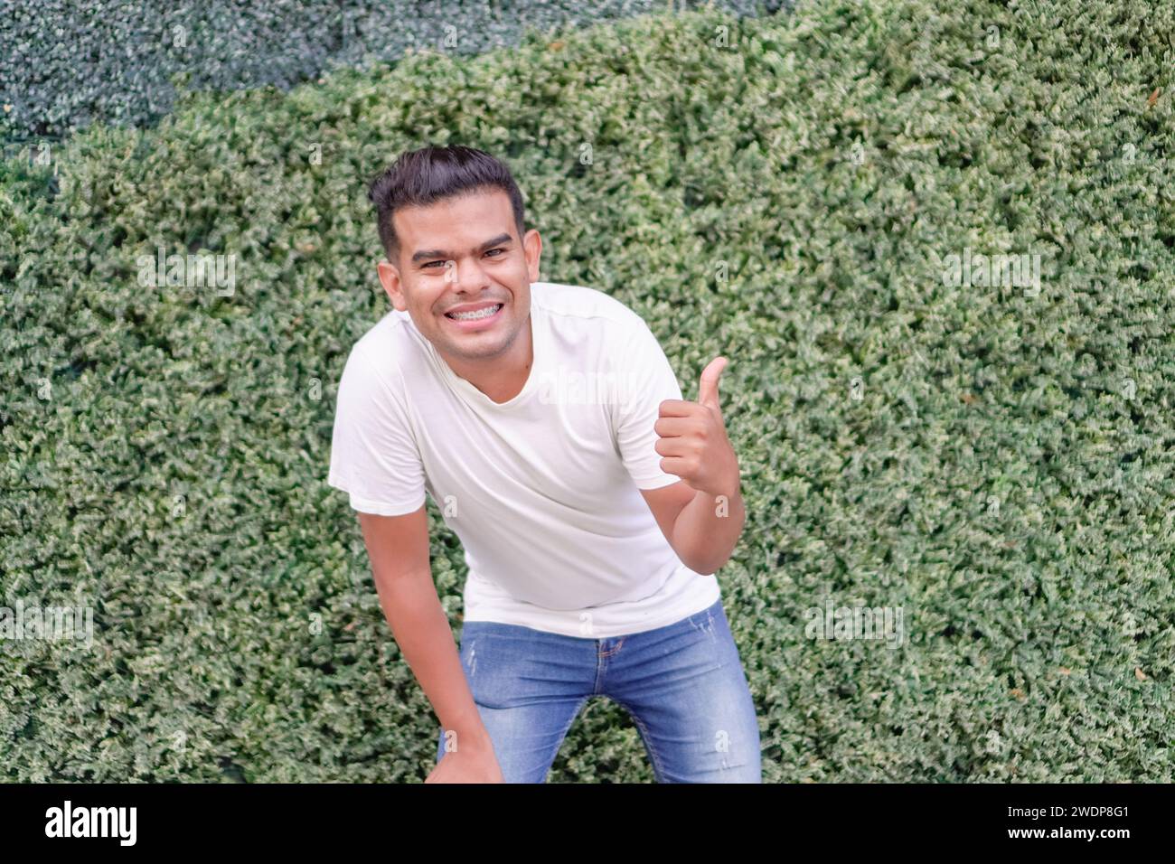 Joyful man wearing braces on teeth, showing thumbs up with green ...