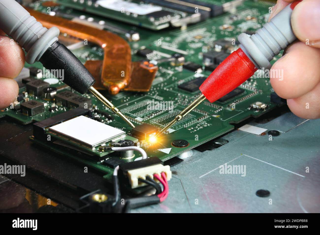 Technician checking electronics part on circuit board with probe of digital multimeter ...