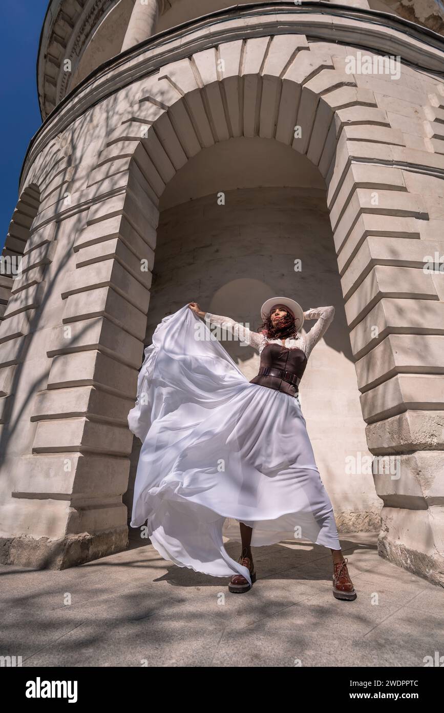 Stylish woman building city. A dancer in a long white skirt dances in ...