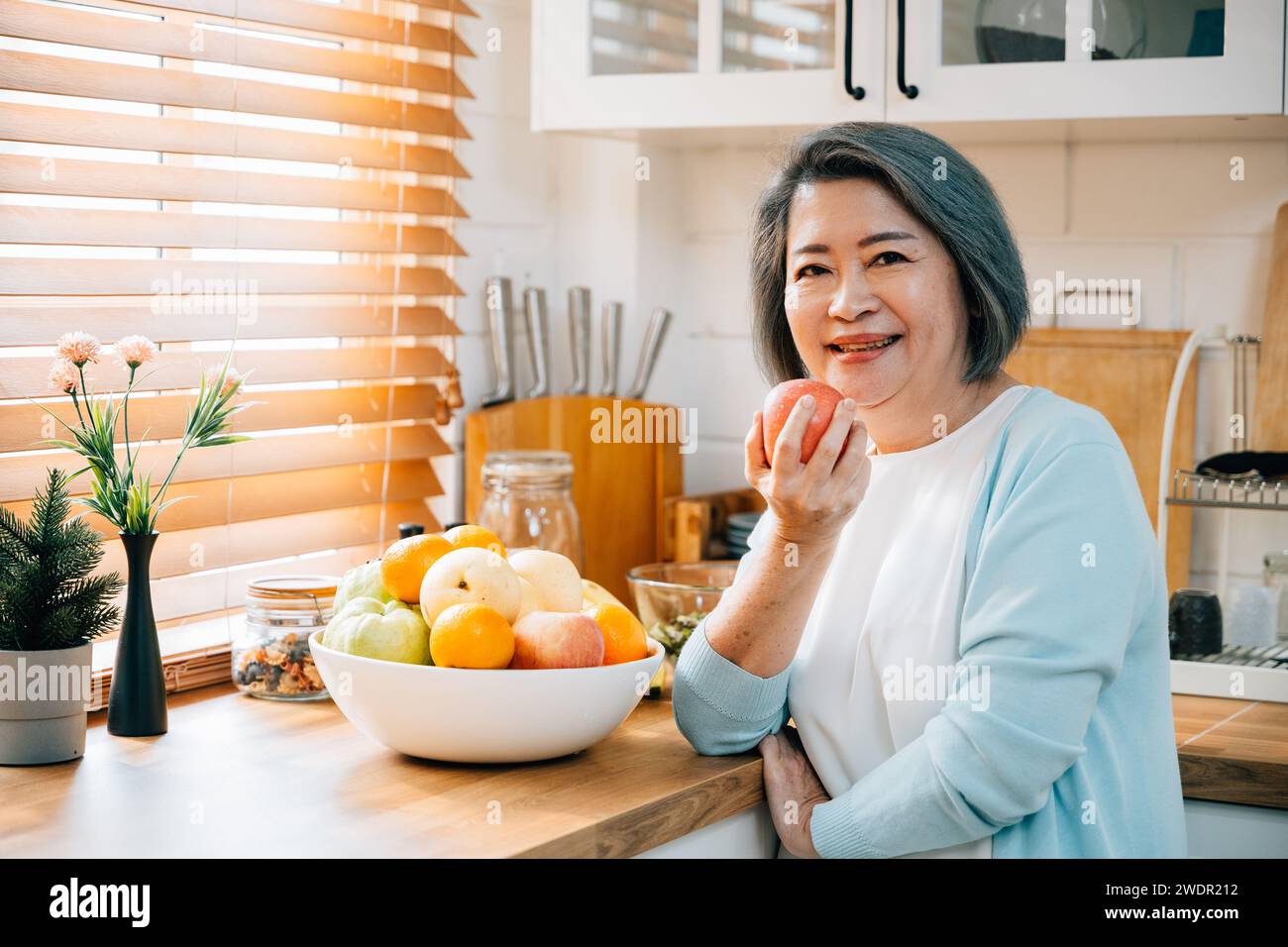 In the kitchen, a happy old woman, a grandmother, enjoys cooking and ...