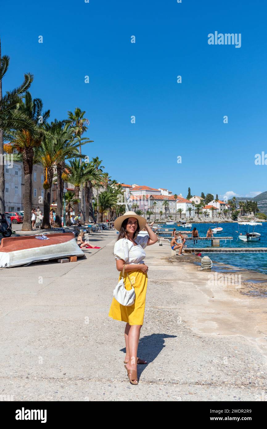 A woman in stylish summer clothes at the seafront with piers, palm ...