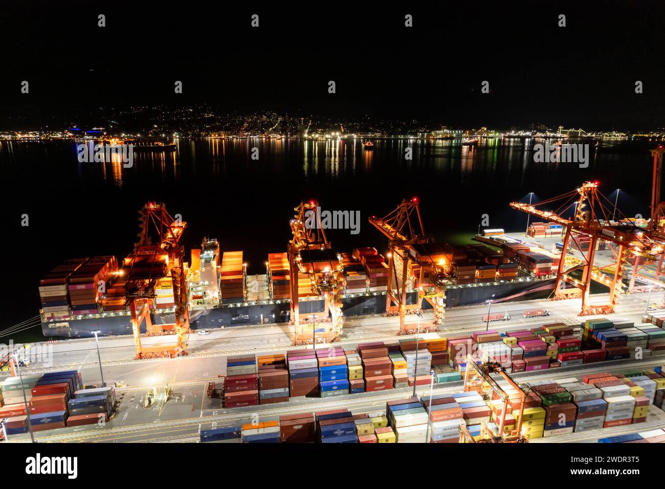 Aerial photo of cargo terminal loading shipping containers onto cargo ships, marine terminal ...
