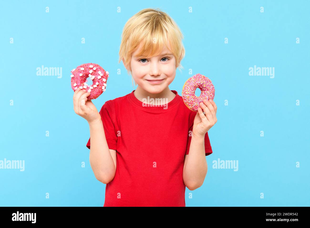 Cute little boy with blond hair and freckles having fun with glazed ...