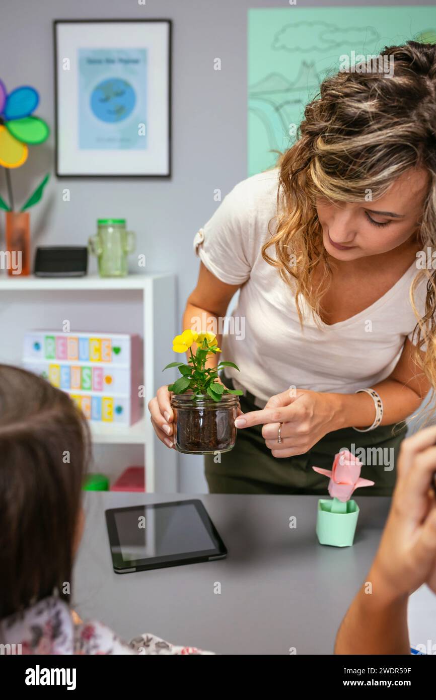 Female teacher showing pansy plant roots to her students in ecology ...