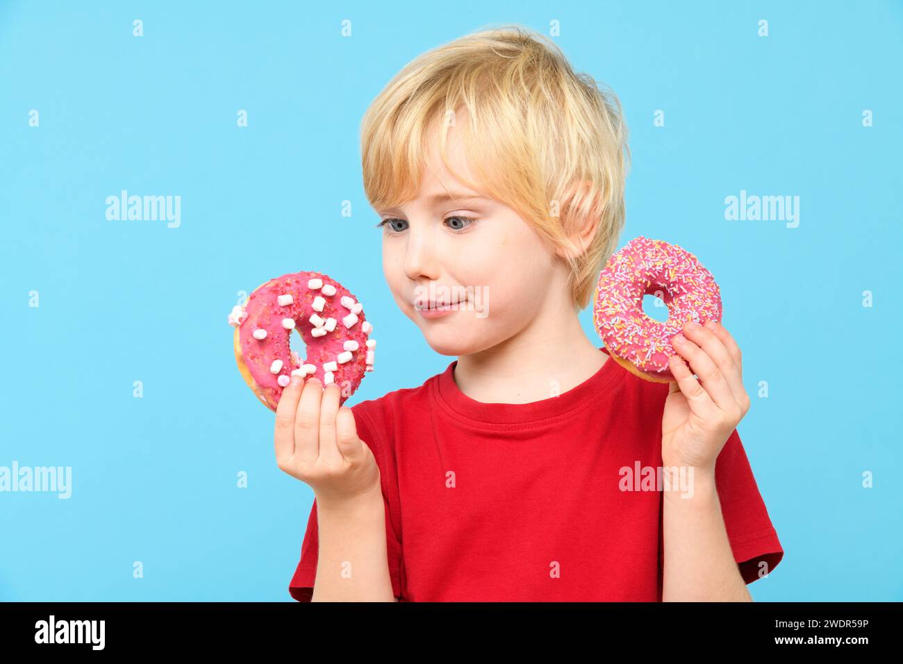 Cute little boy with blond hair and freckles having fun with glazed ...