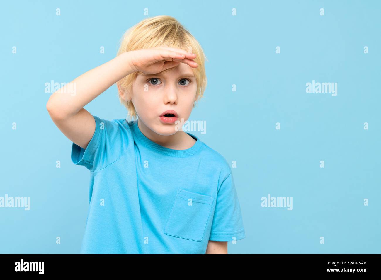 Cute preschooler looking curiously into distance with hand on the ...
