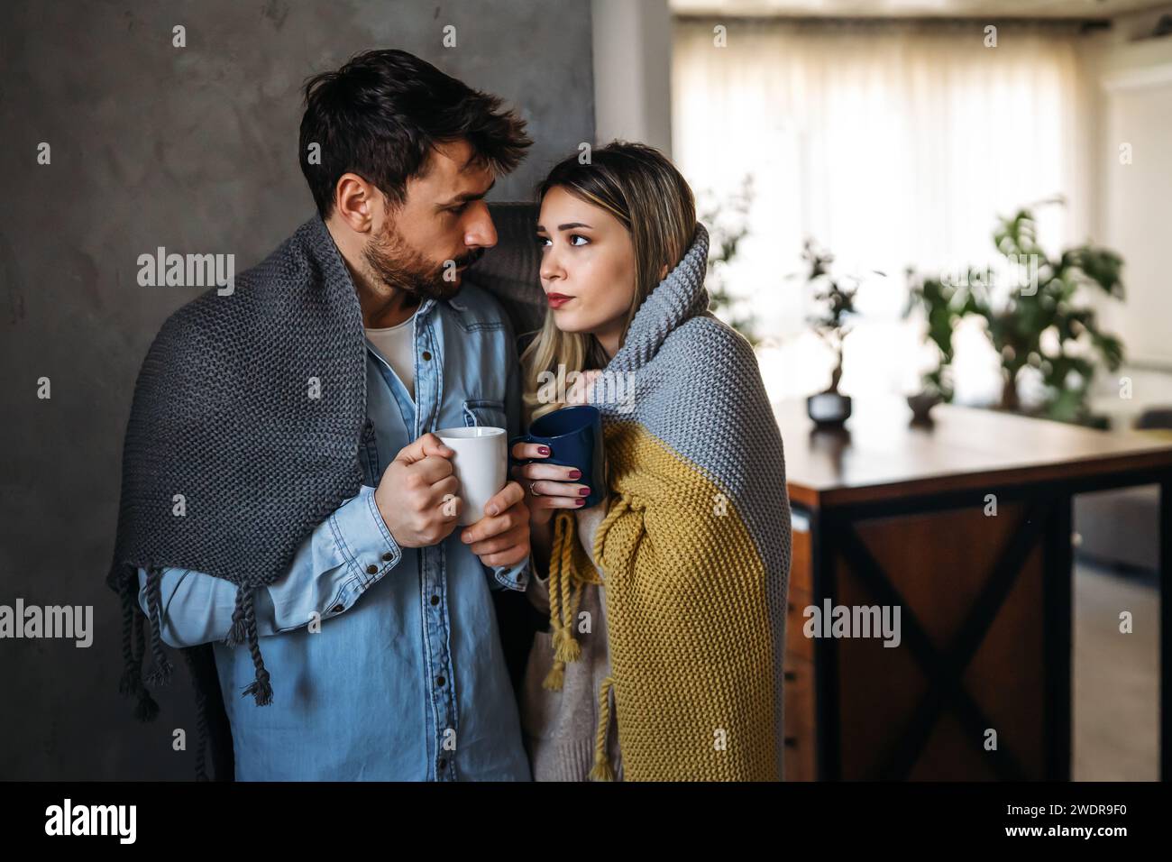 Freezing couple covered with a blanket. Man and a woman wrapped in a ...