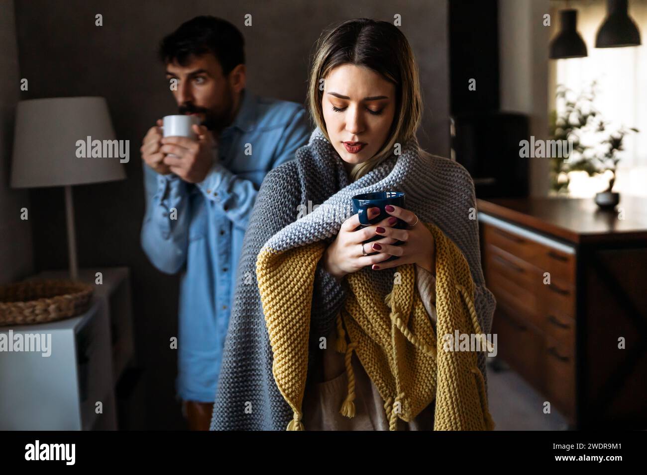 Freezing couple covered with a blanket. Man and a woman wrapped in a ...