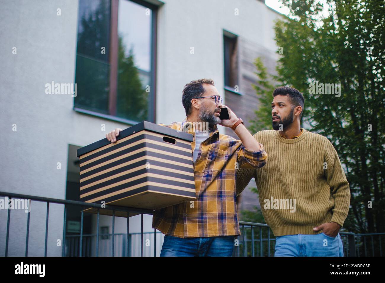 Man helping his friend move into new apartment in building. Man is ...