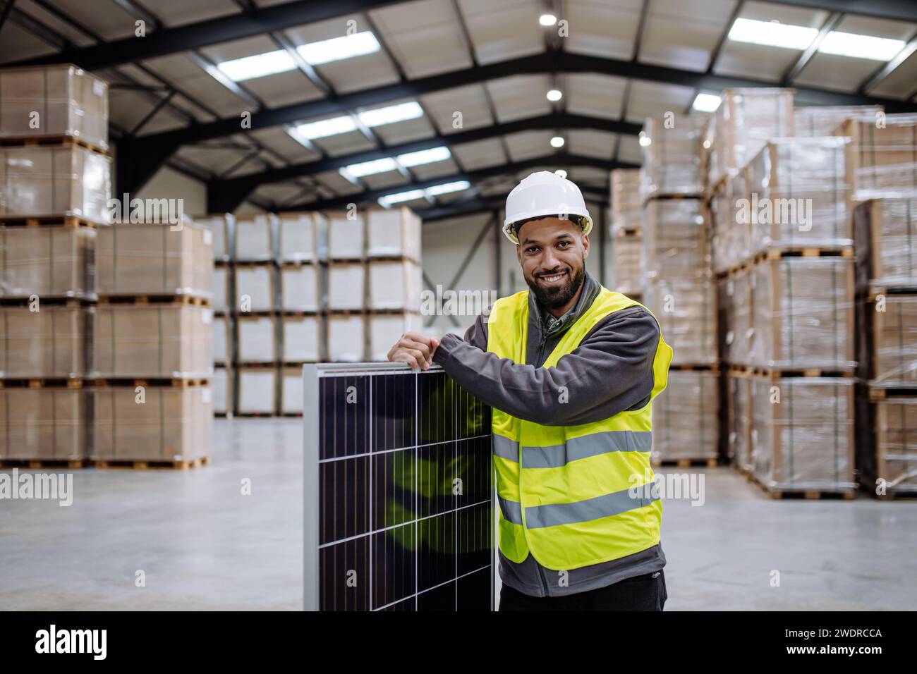 Handsome worker carrying solar panel in warehouse, factory. Solar panel ...