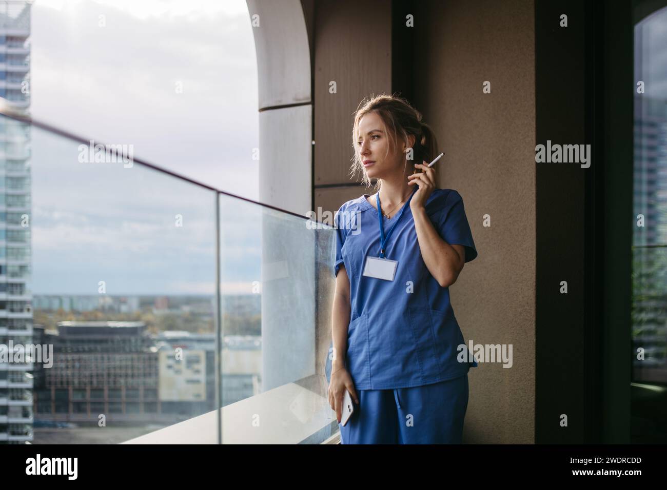 Female nurse smoking cigarette at balcony after work. Doctor feeling ...
