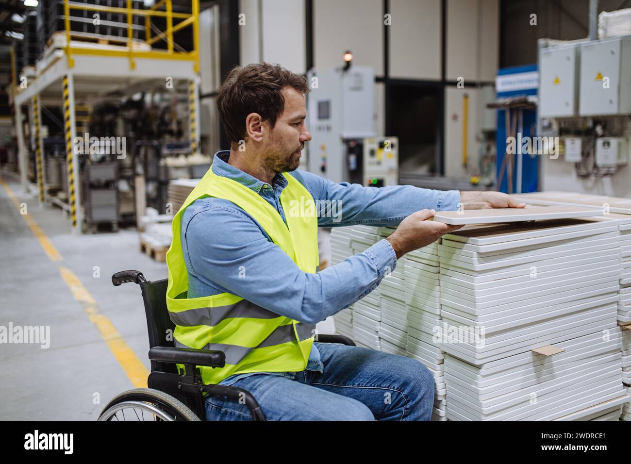 Portrait of man in wheelchair working in modern industrial factory ...