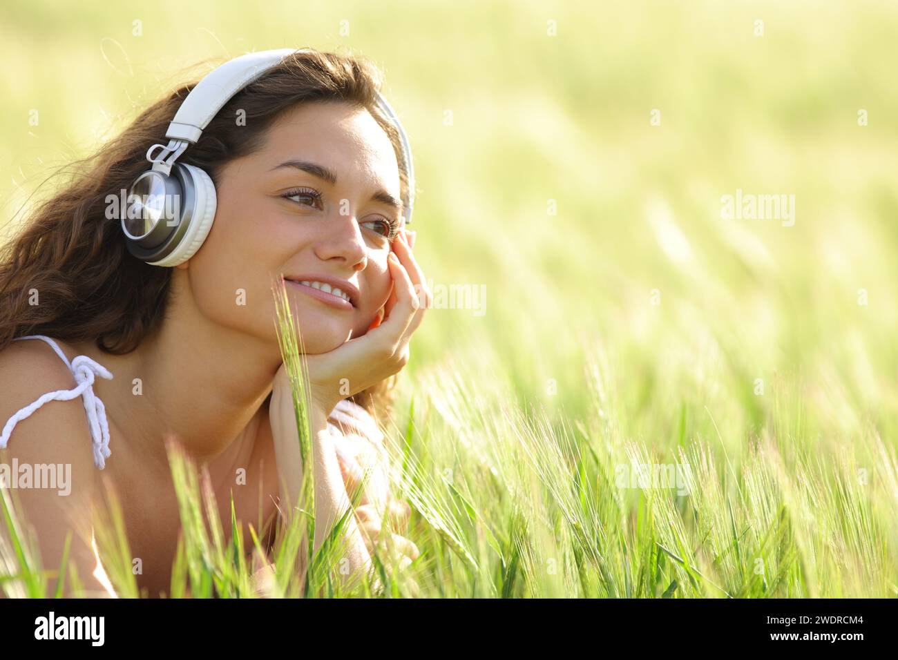Relaxed woman listening music with headphones in a green field Stock ...