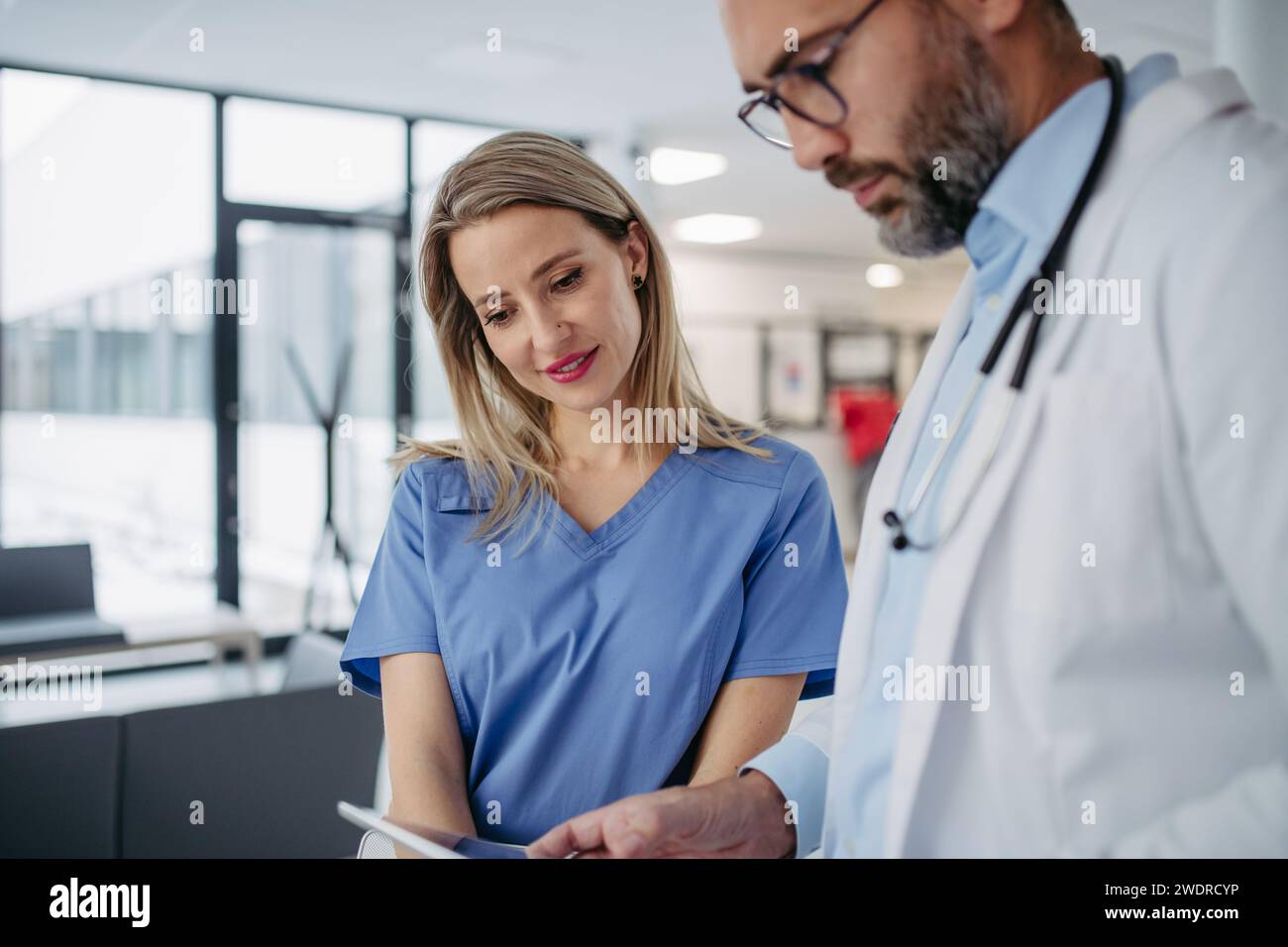 Doctor and nurse looking at test results on tablet, talking about ...