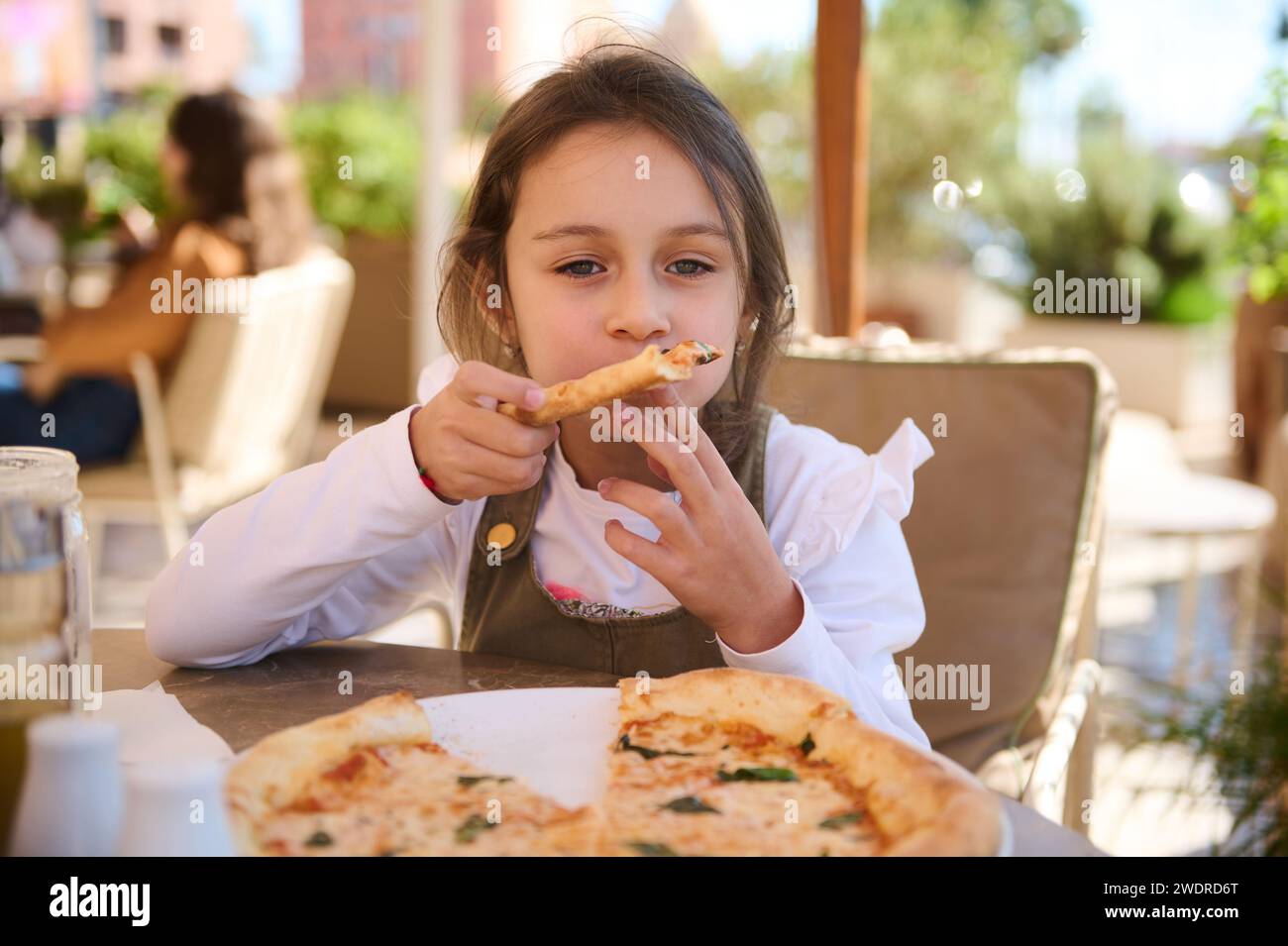Close-up of a Caucasian adorable little kid girl biting a slice of ...