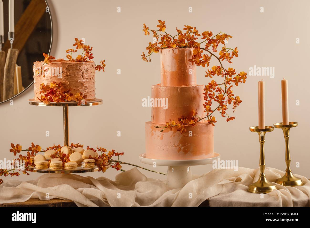 Tall peach colored wedding cake decorated with branch on sweet table ...