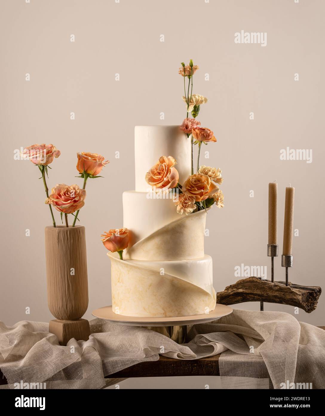Three tiered wedding cake decorated with peach fuzz colored flowers ...