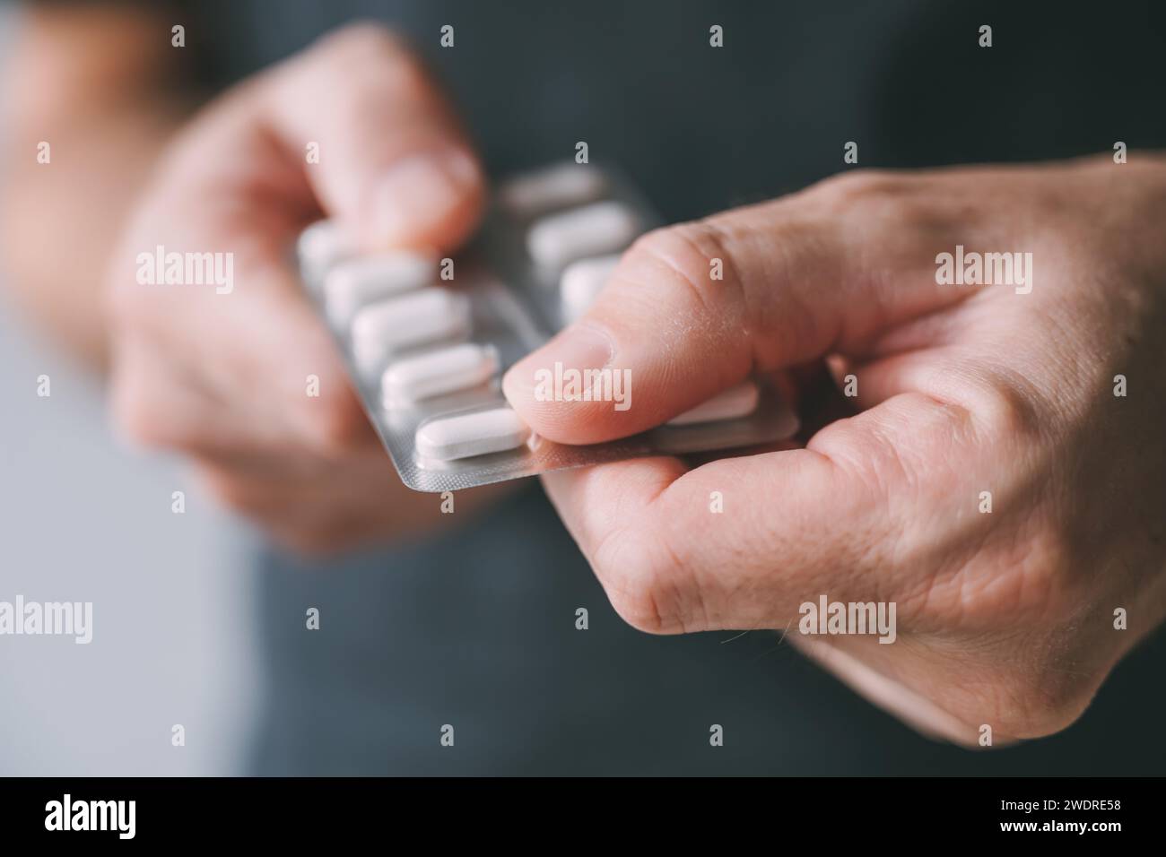 Man taking medicine from blister pack, closeup of hands with selective ...